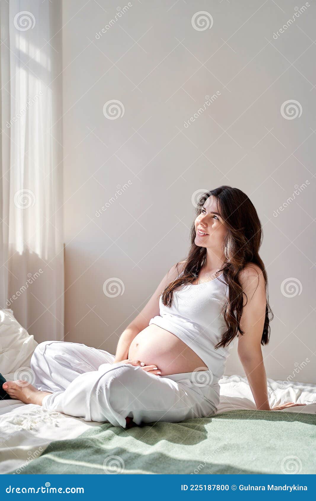 A Beautiful Pregnant Girl Holds Her Stomach With Her Hands And Smiles