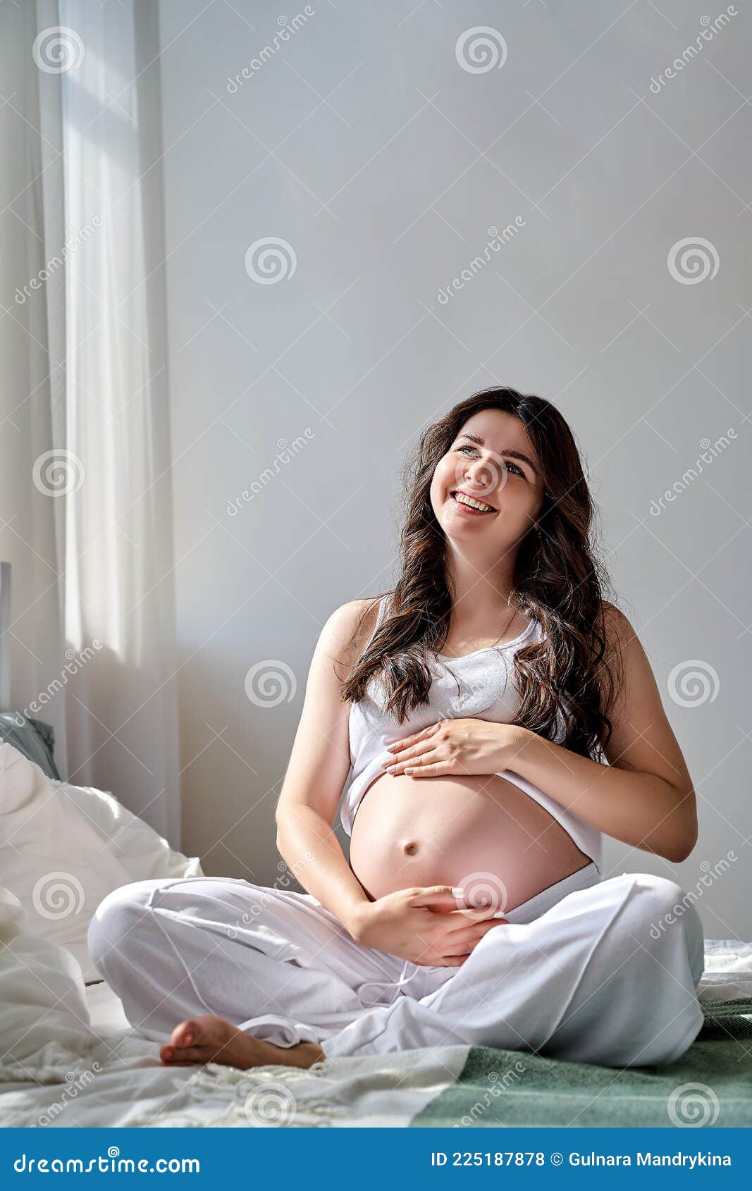A Beautiful Pregnant Girl Holds Her Stomach With Her Hands And Smiles