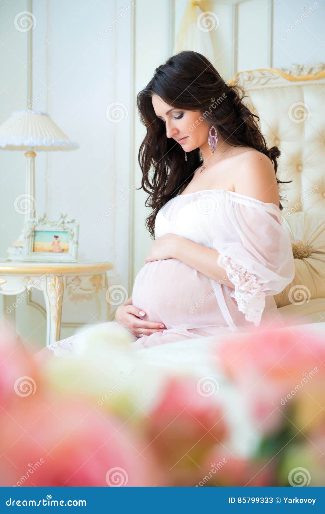 Beautiful Pregnant Girl In A Lace Negligee Sitting On A Bed Stock Image