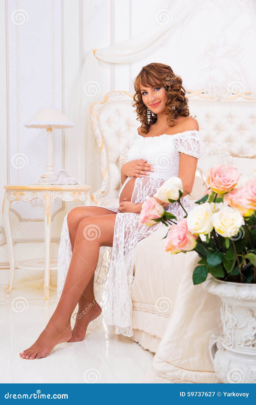 Beautiful Pregnant Girl In A White Lace Dress Sit On A Bed Stock Image