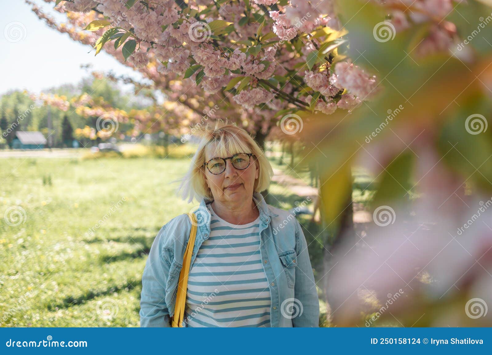 Beautiful 50s Woman Enjoying Sunny Day In Park During Cherry Blossom