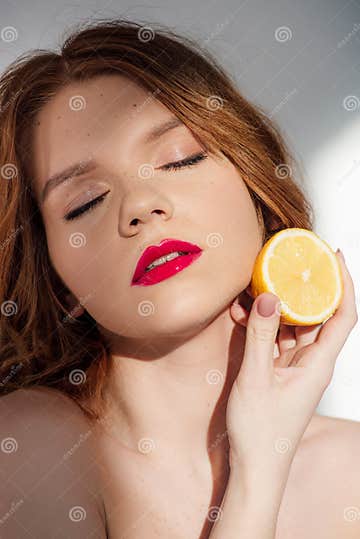 Beautiful Sensual Redhead Girl With Red Lips Posing With Cut Lemon
