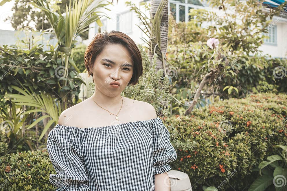 A Beautiful Short Haired Asian Woman Wearing An Off Shoulder Top At A Garden Area Summer Outfit