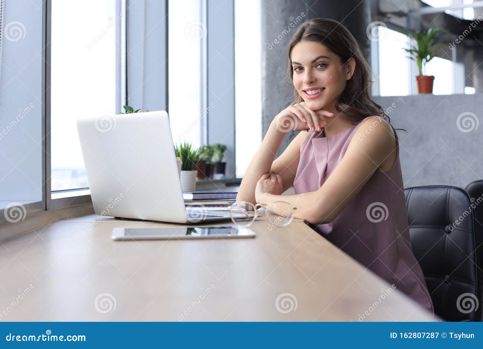 Beautiful Smiling Business Woman is Sitting in the Office and Looking ... Beautiful Smiling Business Woman is Sitting in the Office and Looking ...