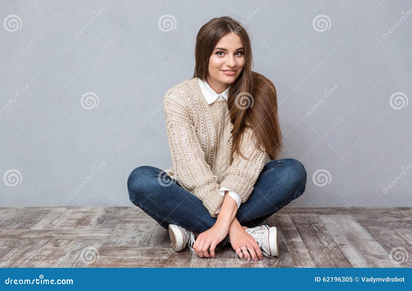 Beautiful Smiling Girl Sitting On The Floor With Legs Crossed Stock