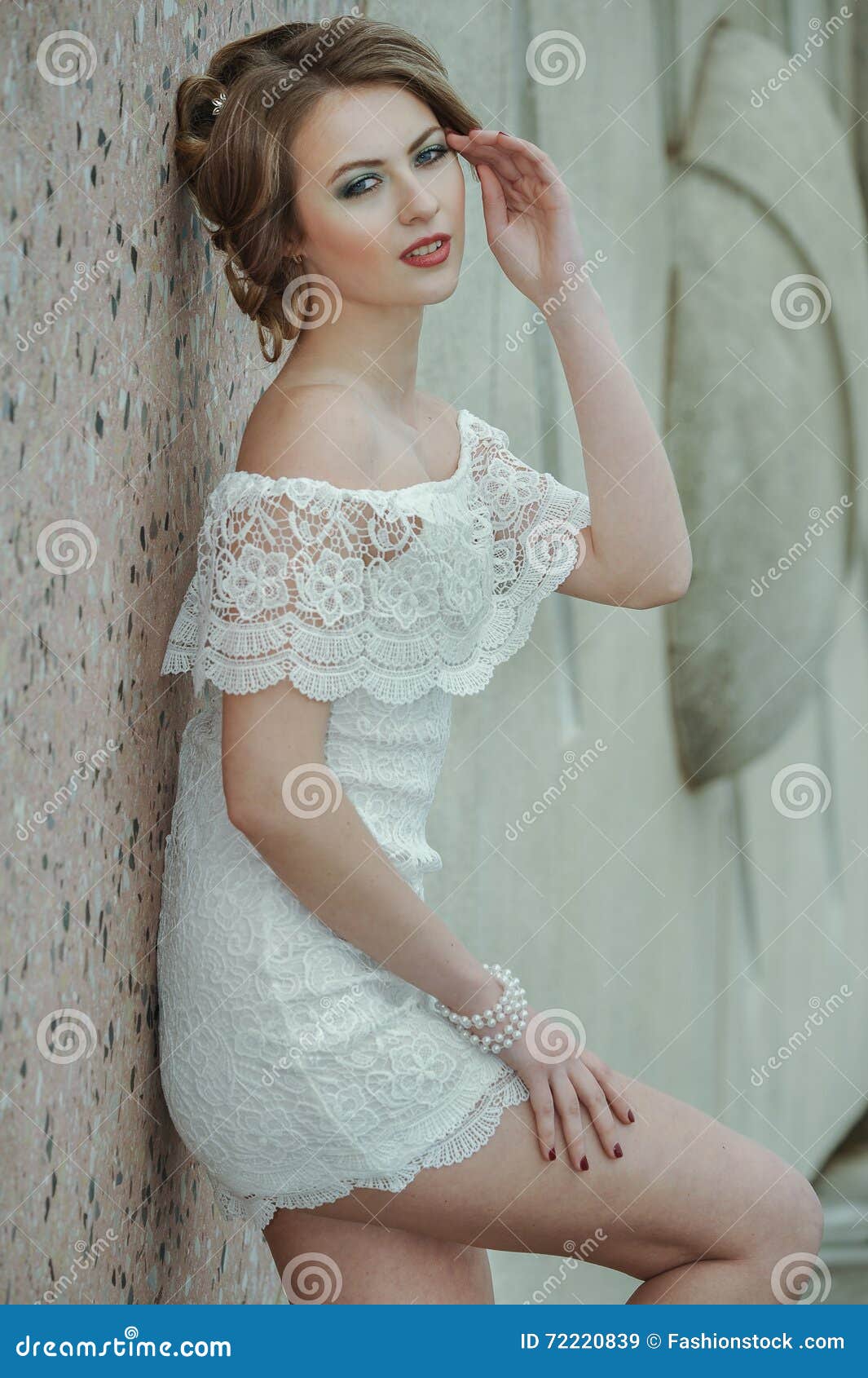 Beautiful Stylish Girl Posing In Short White Dress Against Stone Wall
