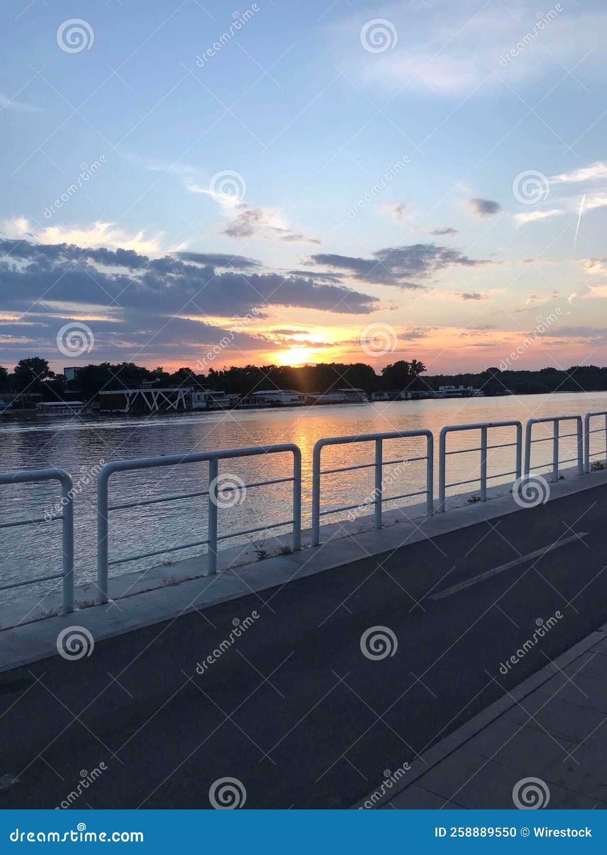 Beautiful Sunset Over a Body of Water Seen from a Shore with Metal ... Beautiful Sunset Over a Body of Water Seen from a Shore with Metal ...