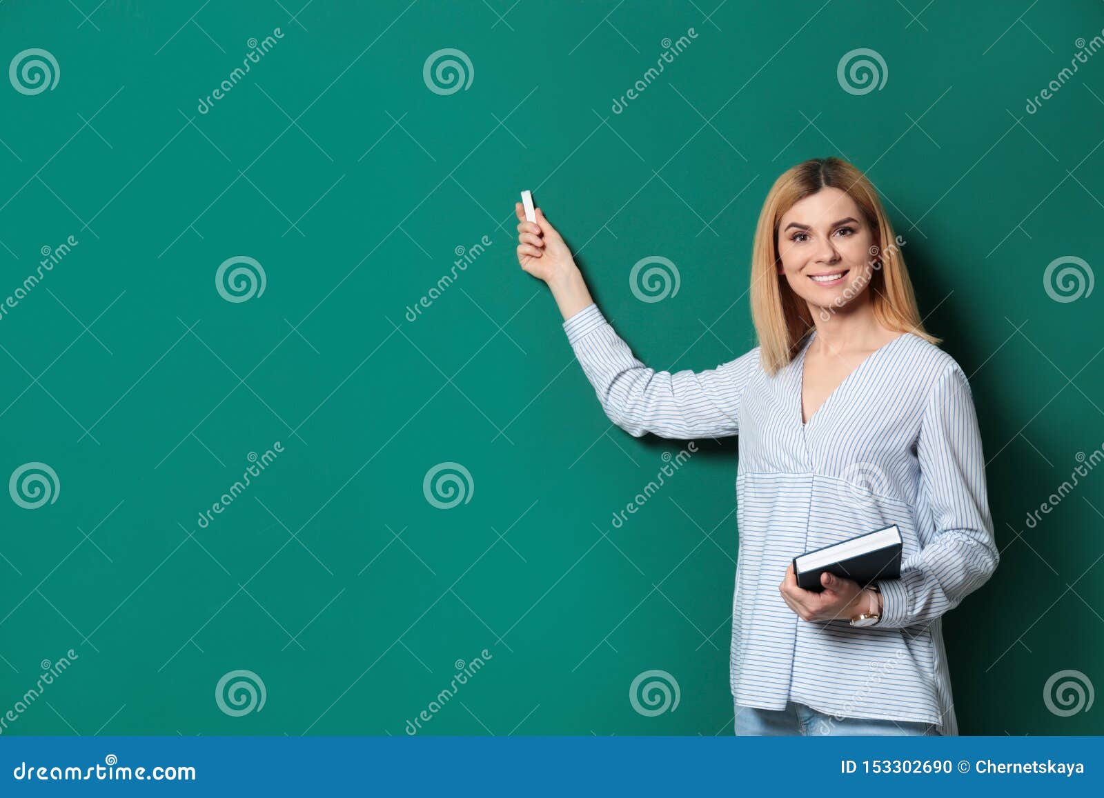 Beautiful Teacher with Book Pointing at Chalkboard Stock Photo - Image ...