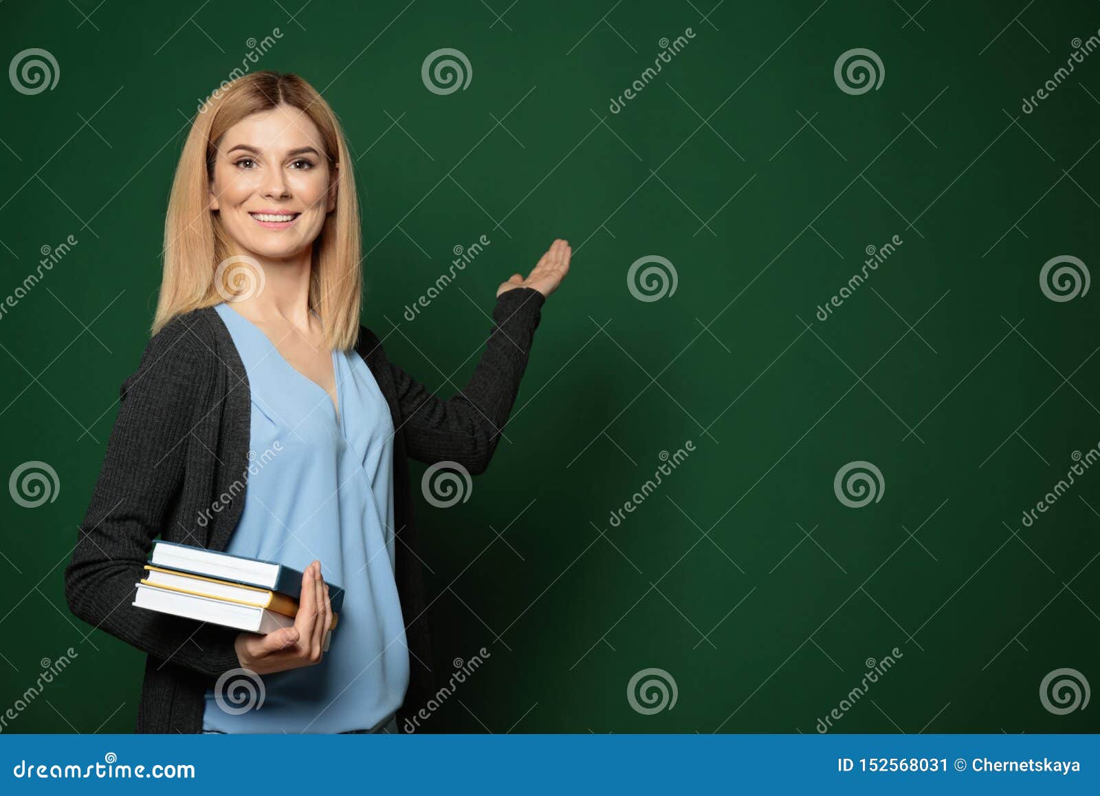 Beautiful Teacher with Books Pointing at Chalkboard Stock Image - Image ...