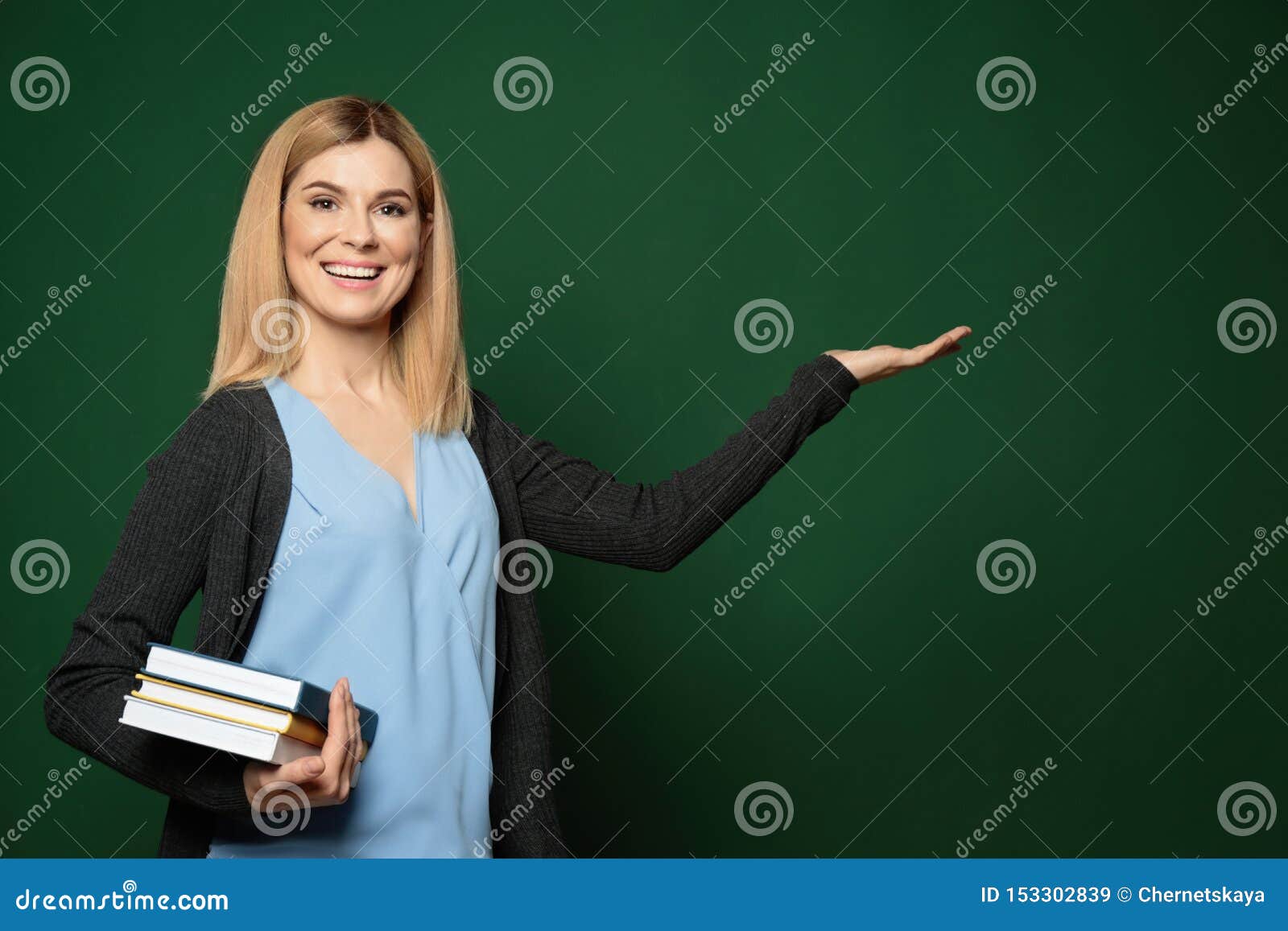 Beautiful Teacher with Books Pointing at Chalkboard Stock Image - Image ...