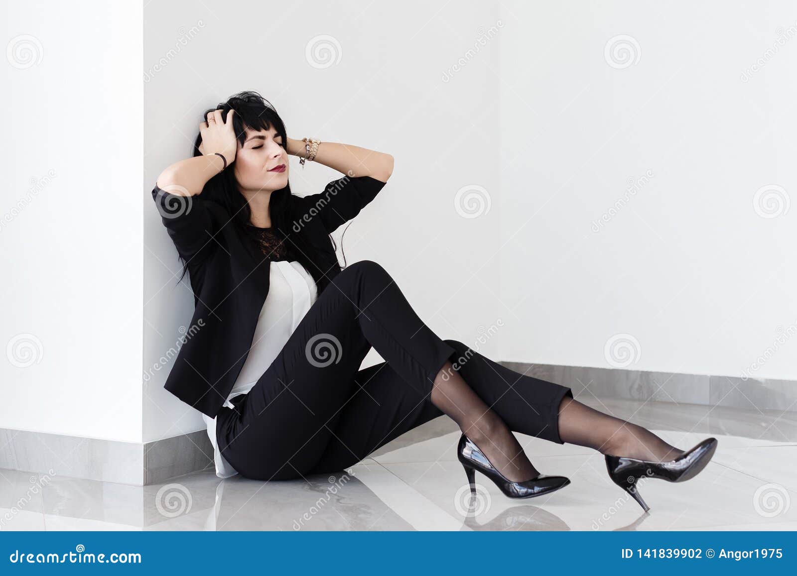 Beautiful Tired Young Woman Dressed In A Black Business Suit Sits On