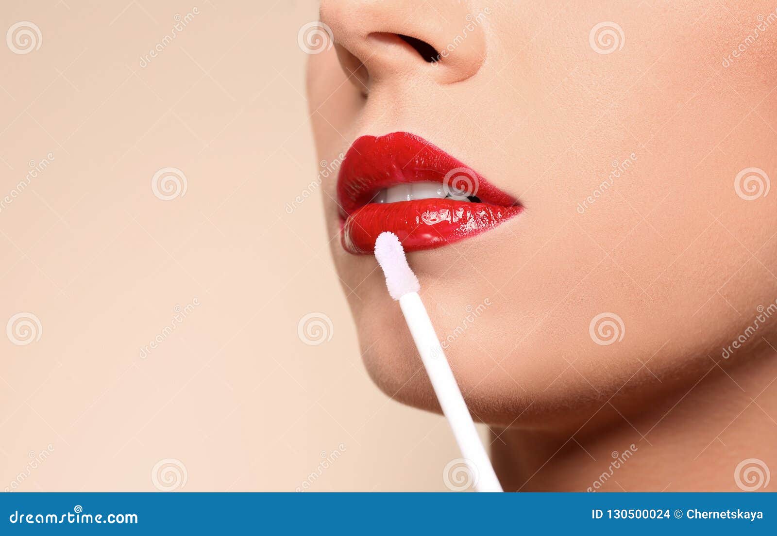 Beautiful Woman Applying Red Gloss On Lips Against Color Background