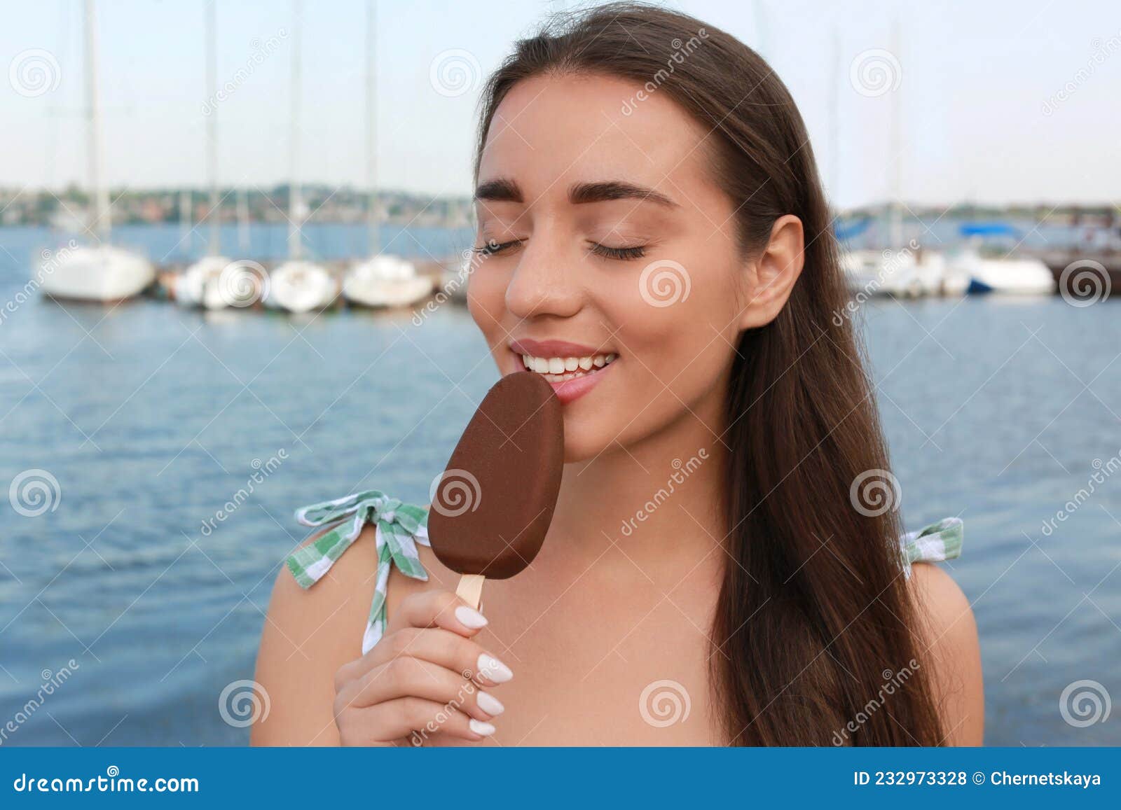 Beautiful Young Woman Eating Ice Cream Glazed In Chocolate Near River