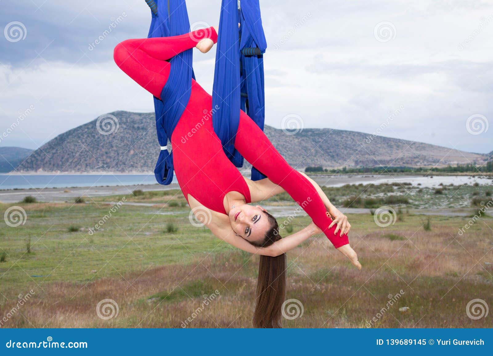 Beautiful Woman Engaged In Antigravity Yoga Outdoors By The Sea On The