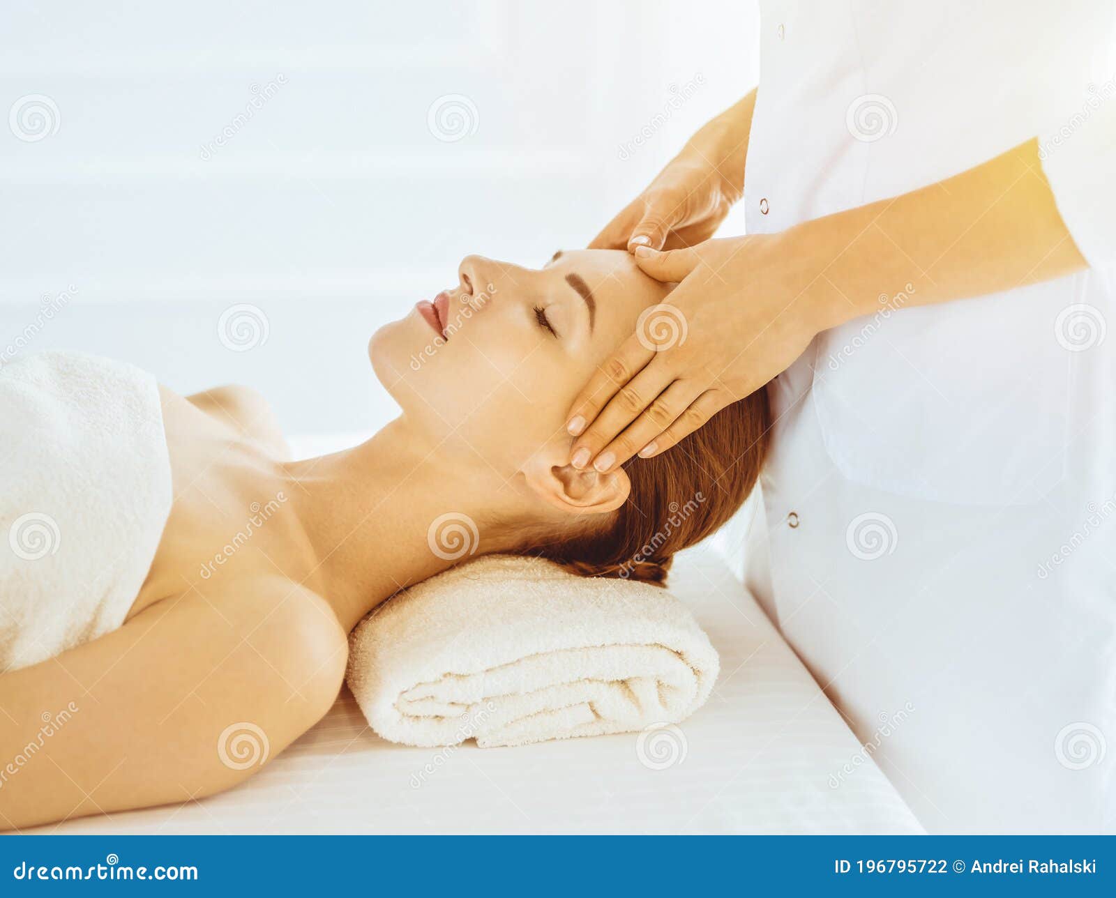Beautiful Woman Enjoying Facial Massage With Closed Eyes In Sunny Spa