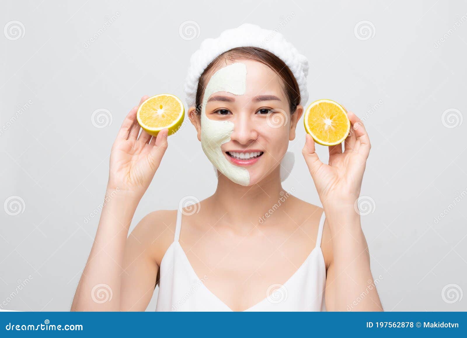 Beautiful Woman Is Getting Facial Clay Mask And Holding Orange Pieces