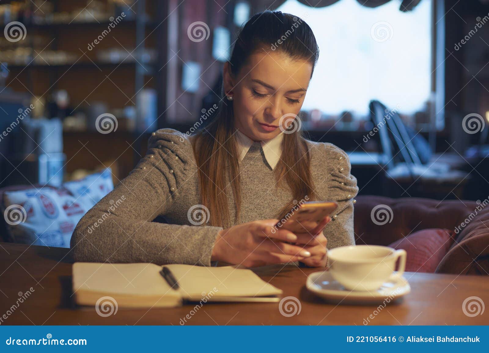 Beautiful Woman Sitting In A Cafe At A Table Drinking Tea And Making