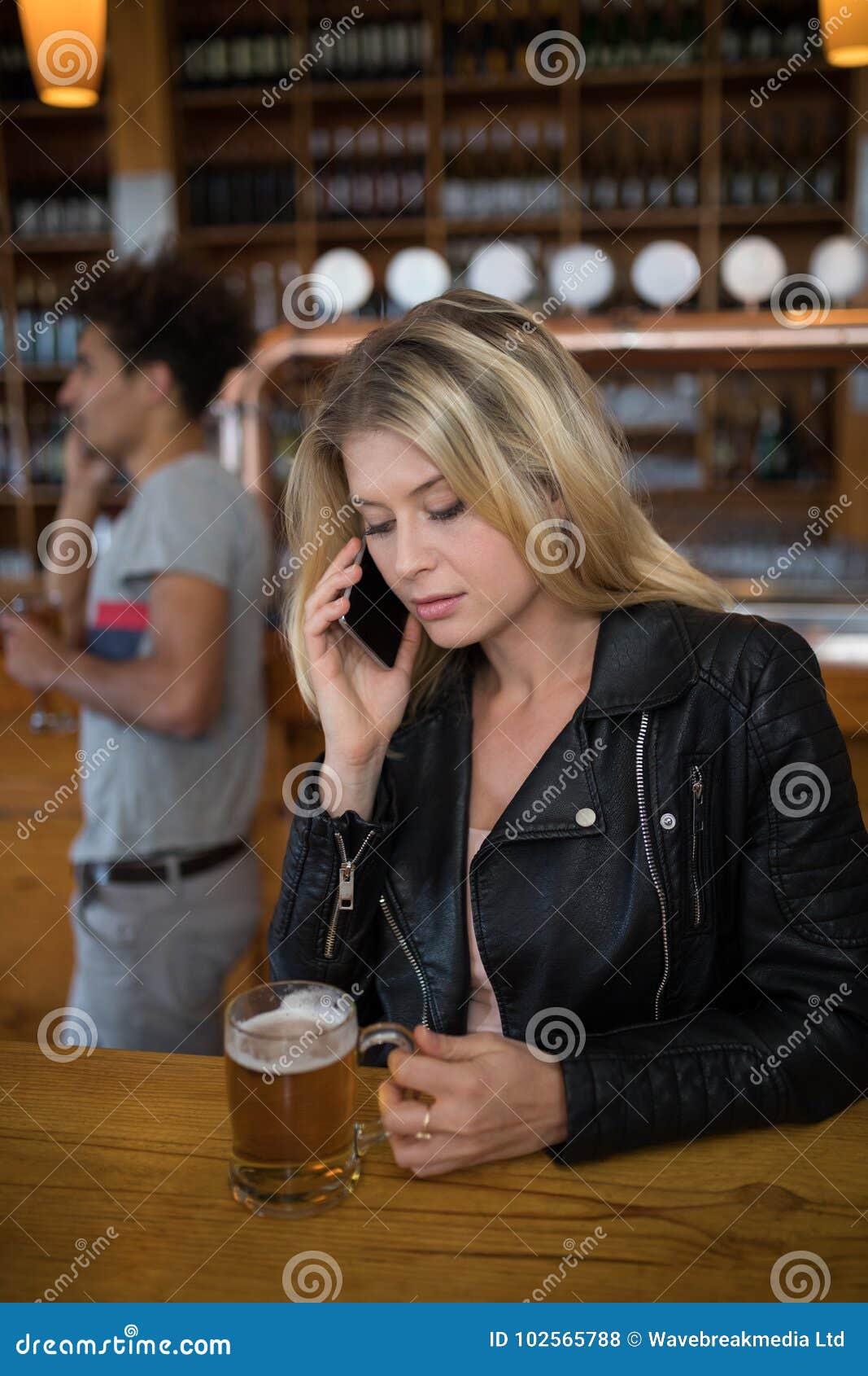 Beautiful Woman Talking On Mobile Phone While Having Glass Of Beer