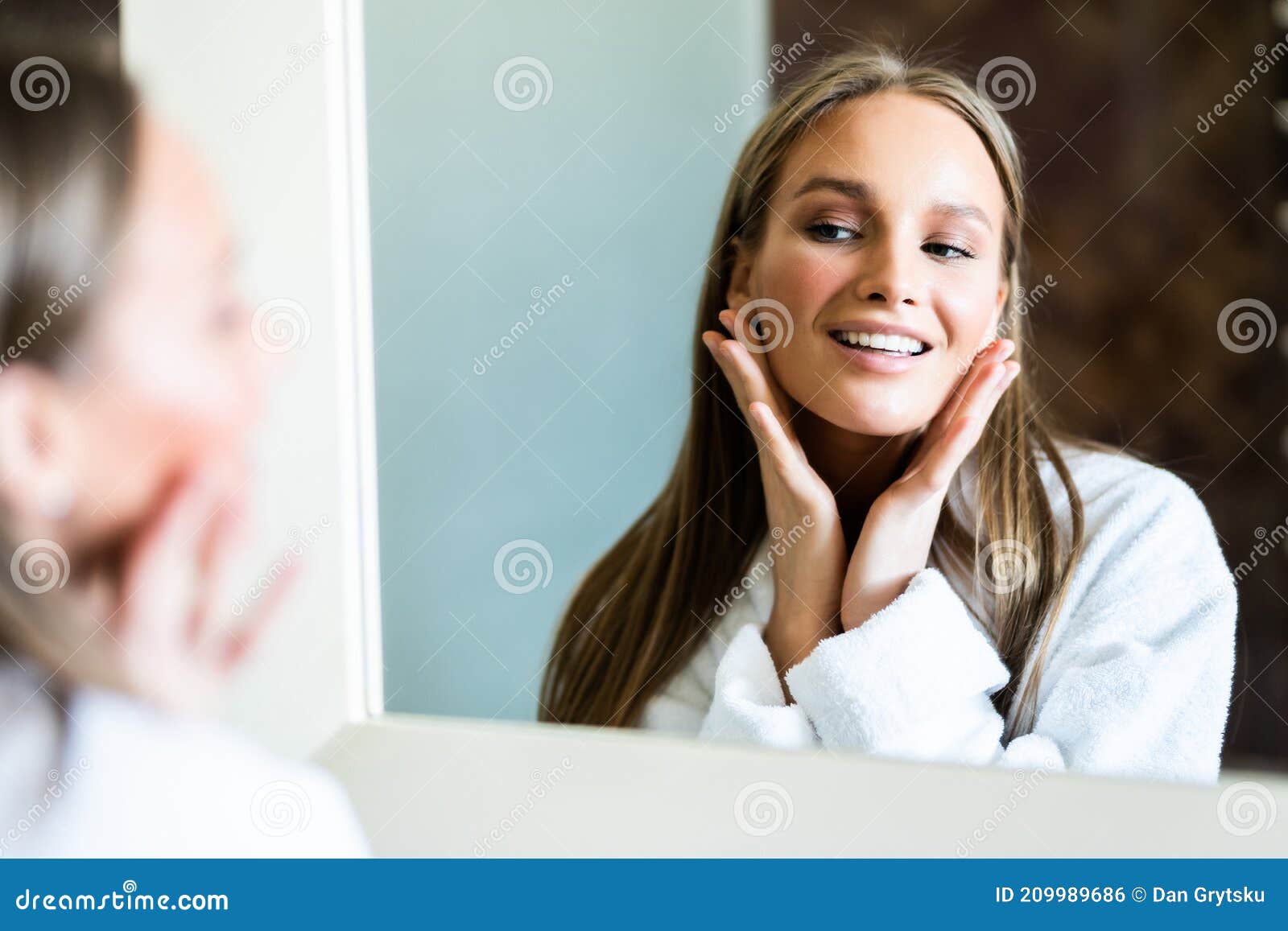 Beautiful Young Woman Is Touching Her Face And Smiling While Looking At