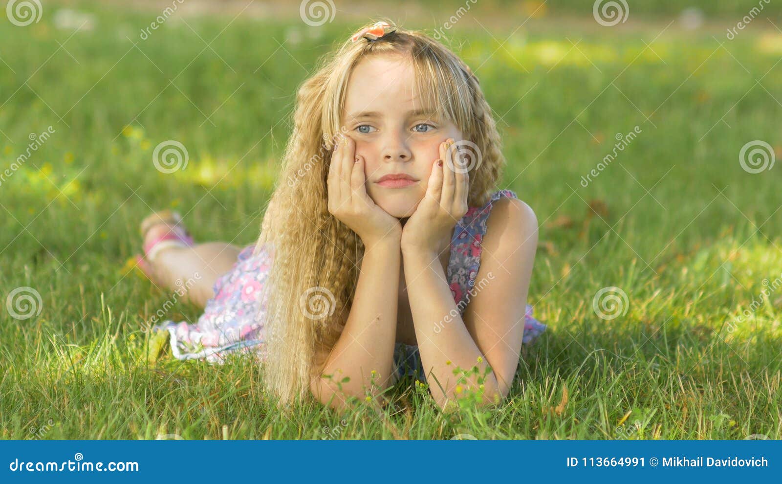Beautiful Young Blonde Girl Lying On A Field Green Grass Outdoors