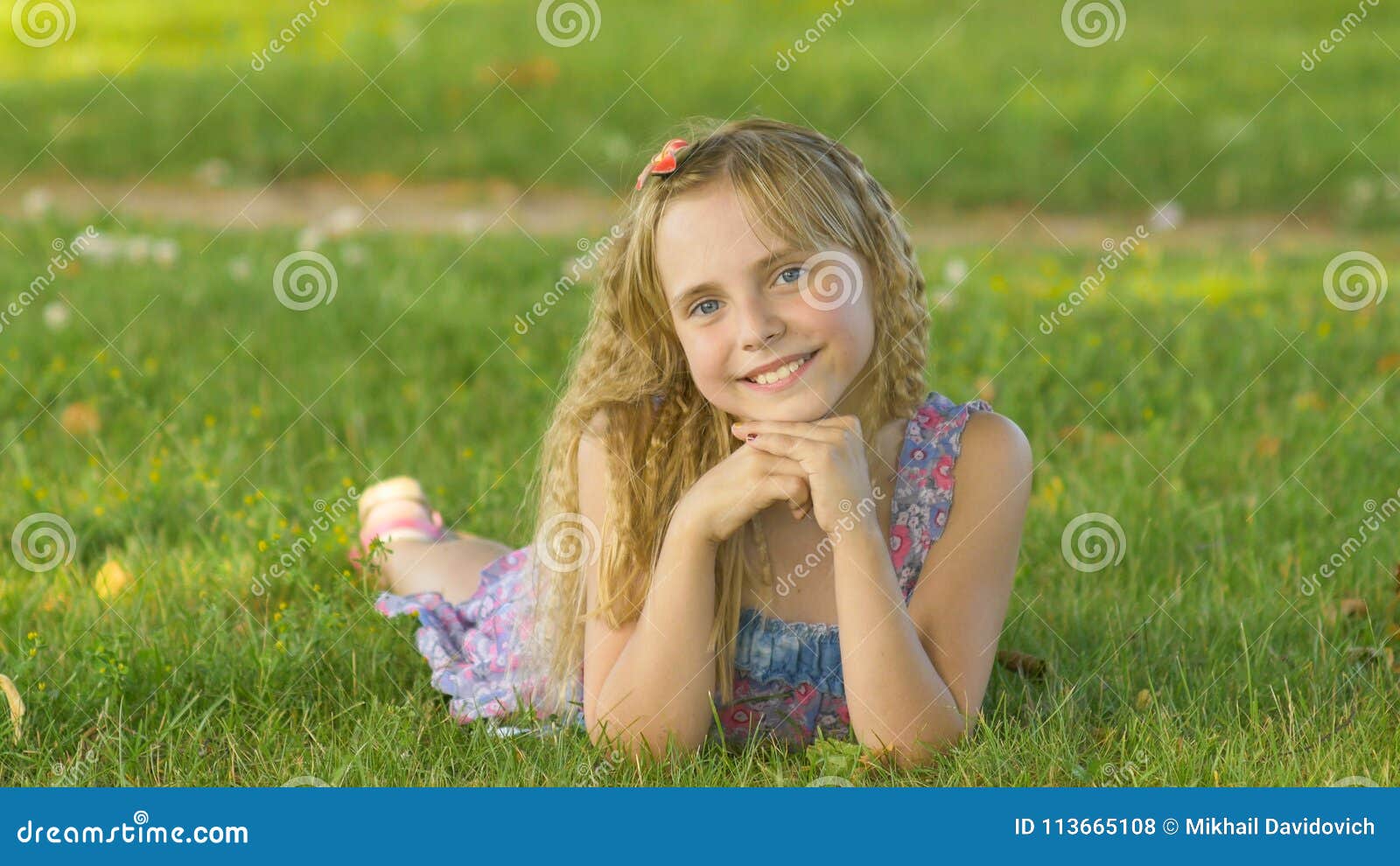 Beautiful Young Blonde Girl Lying On A Field Green Grass Outdoors