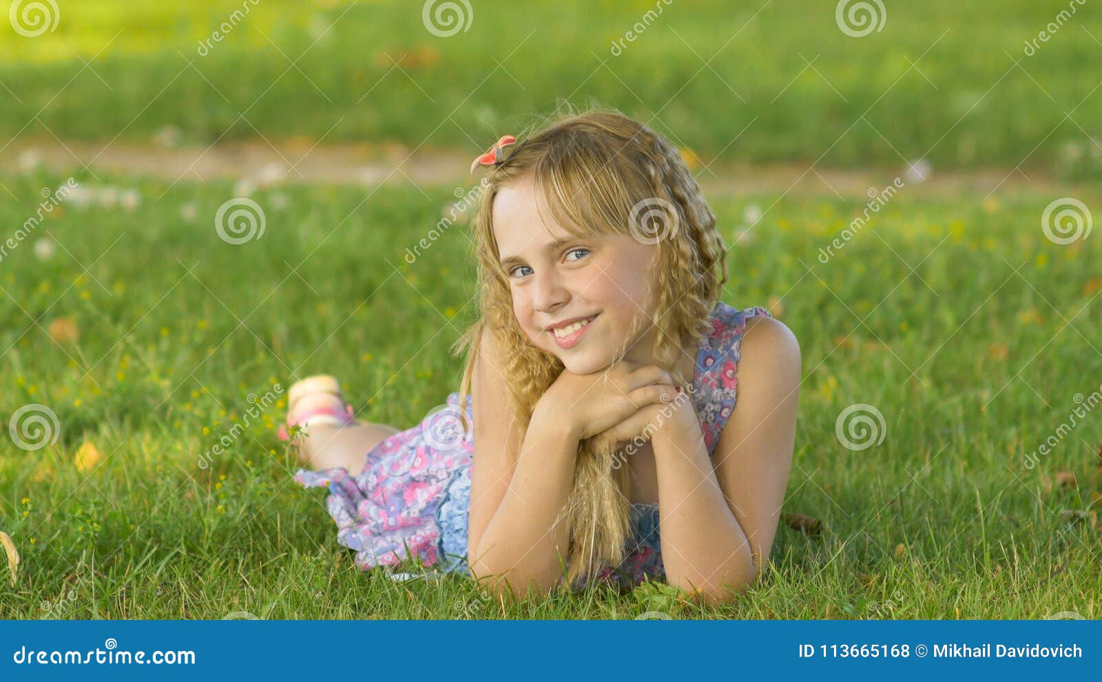 Beautiful Young Blonde Girl Lying On A Field Green Grass Outdoors