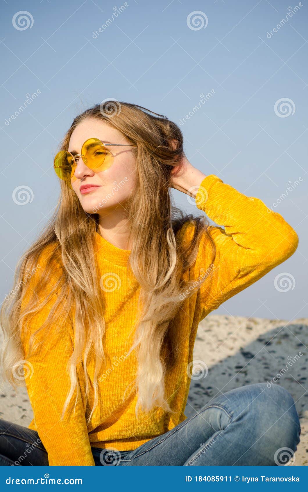 Beautiful Young Blonde Girl In Yellow Sweater And Jeans Sits On