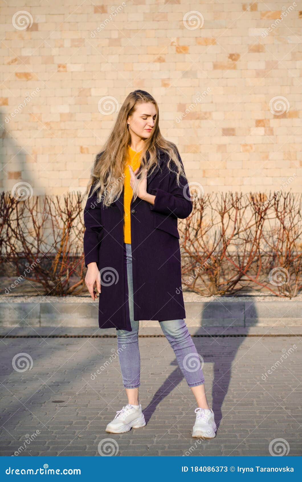 Beautiful Young Blonde Girl In Yellow Sweater White Sneakers And Blue