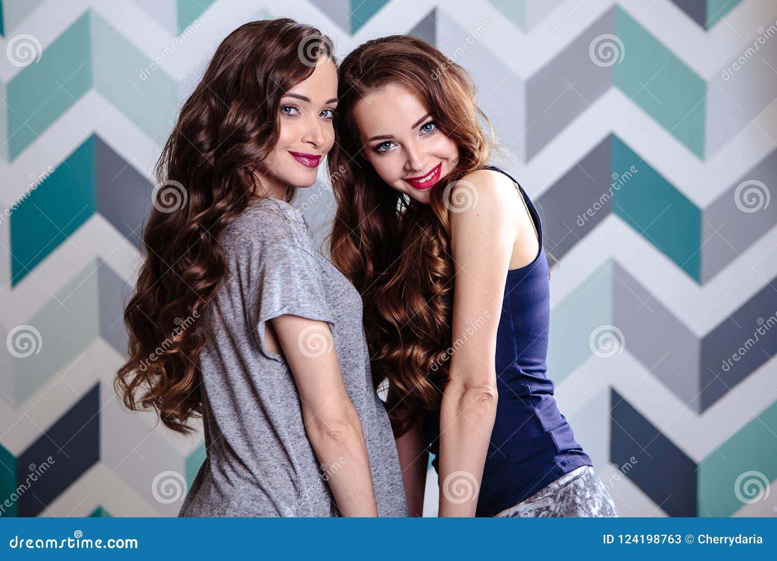 Beautiful Young Brunette Twins Women With Long Curly Hair And Evening Makeup Fashion Beauty