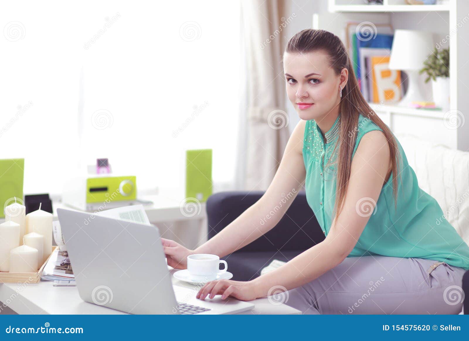 Beautiful Young Brunette Woman At Home Sitting On Sofa Or Settee Using