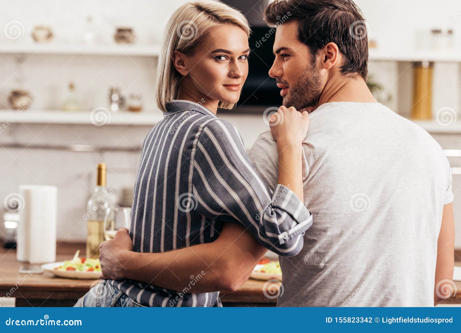 Beautiful Young Couple Hugging in Kitchen and Looking Stock Photo ...