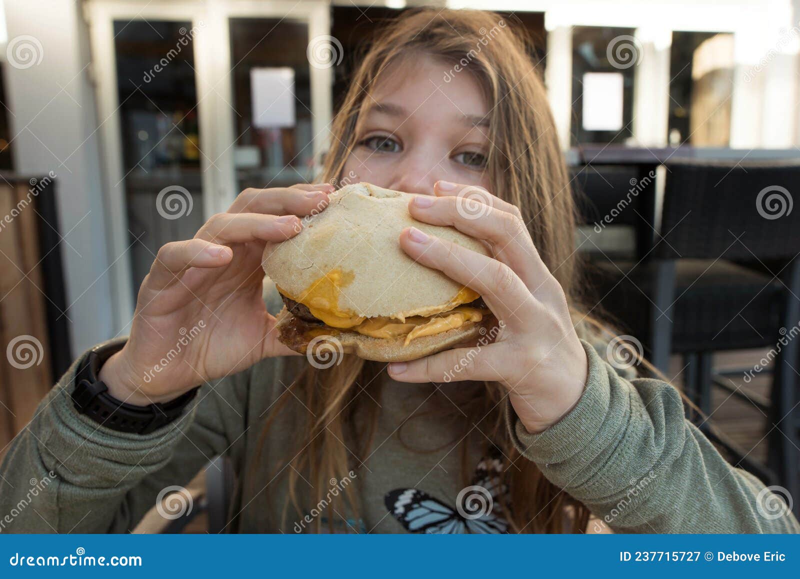 Beautiful Young Girl Eating Hamburger In A Restaurant Stock Image