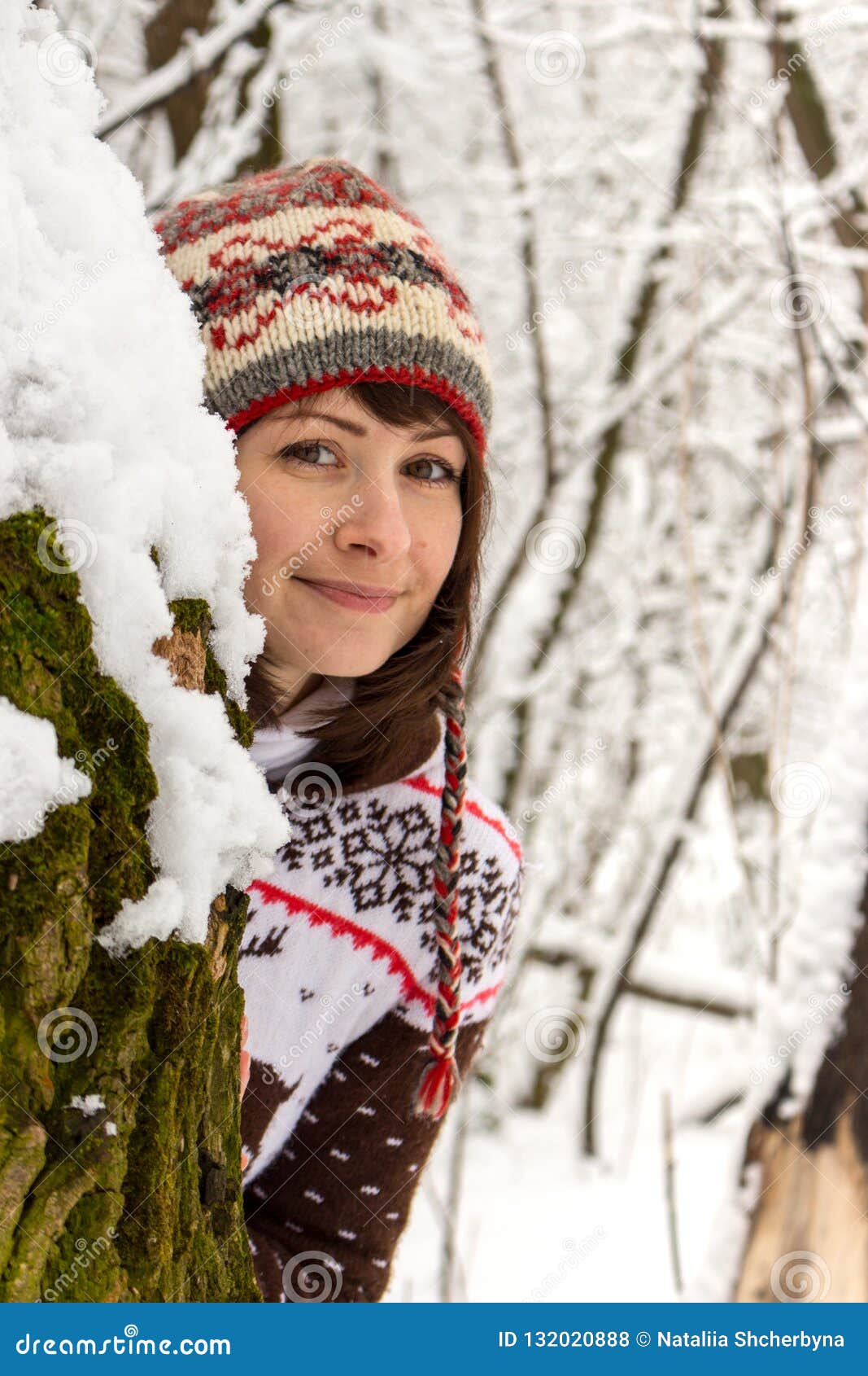 Beautiful Young Girl In Knitted Cozy Wear Looking Out From Behind Tree