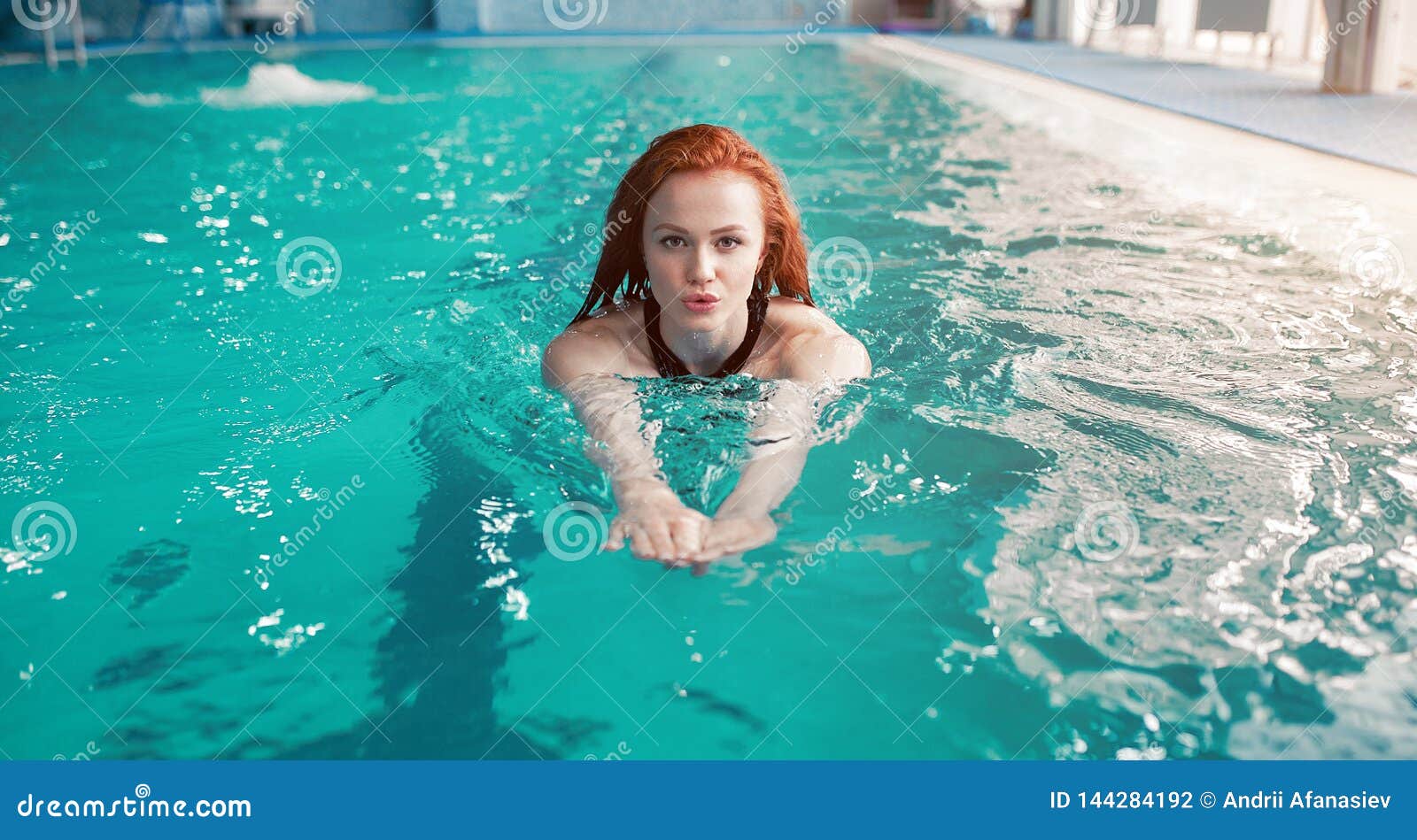 Beautiful Young Redhead Caucasian Girl Swims In The Indoor Swimming
