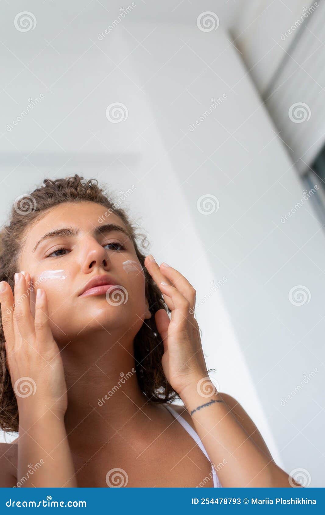 Beautiful Young Woman Applying Cosmetic Cream Treatment On Her Face