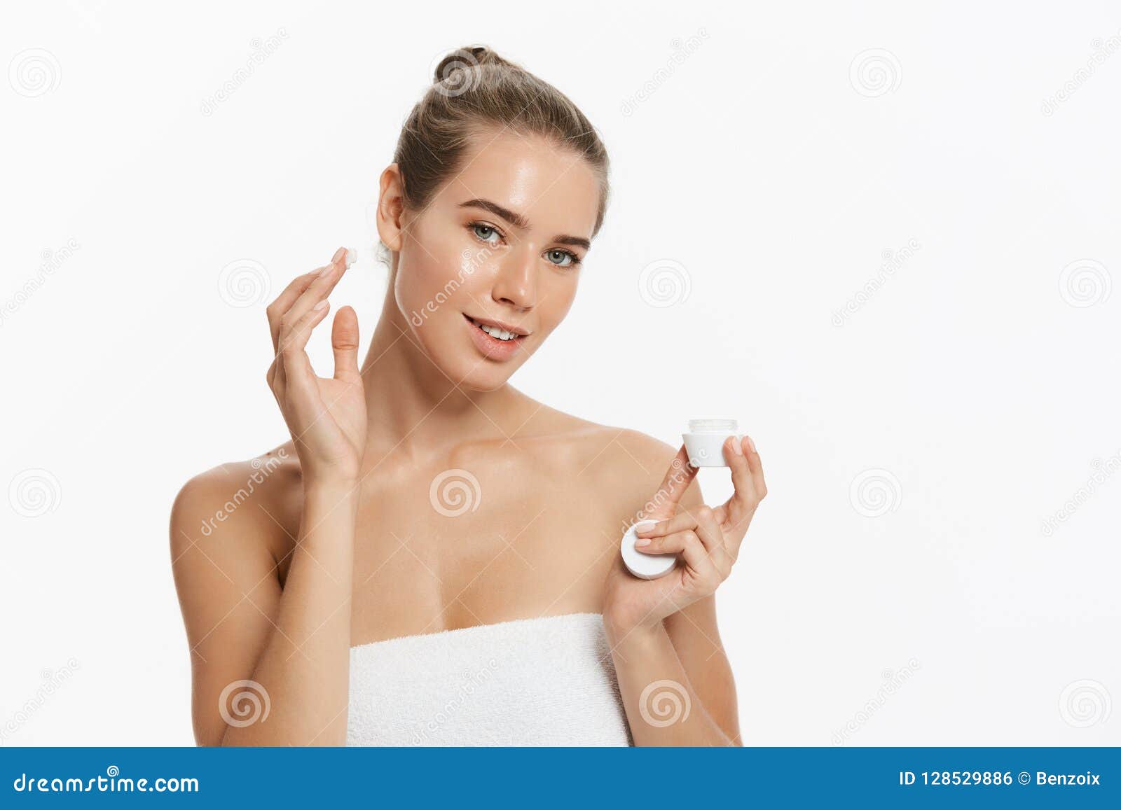 Beautiful Young Woman Applying Cosmetic Cream Treatment On Her Face