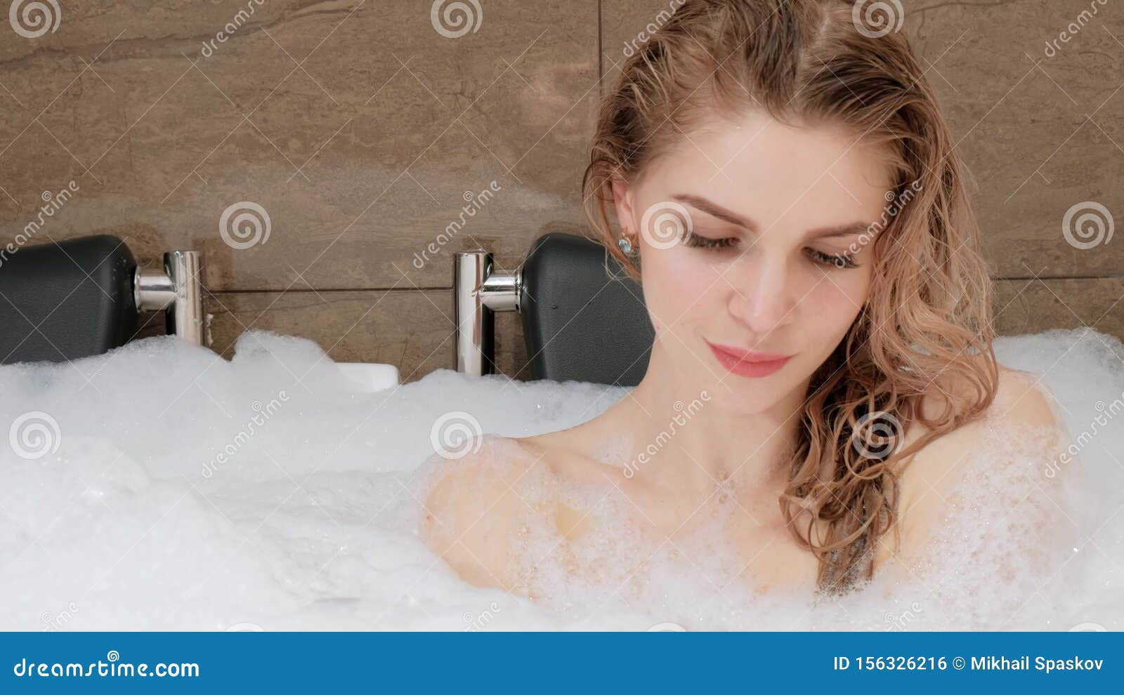 Beautiful Young Woman Blonde Lies In The Bath Tub With Foam Resting