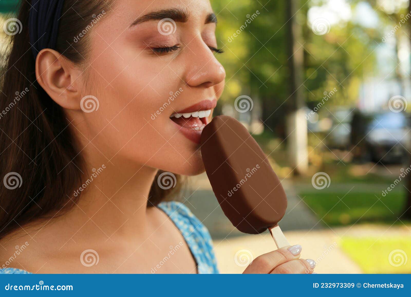 Beautiful Young Woman Eating Ice Cream Glazed In Chocolate On City