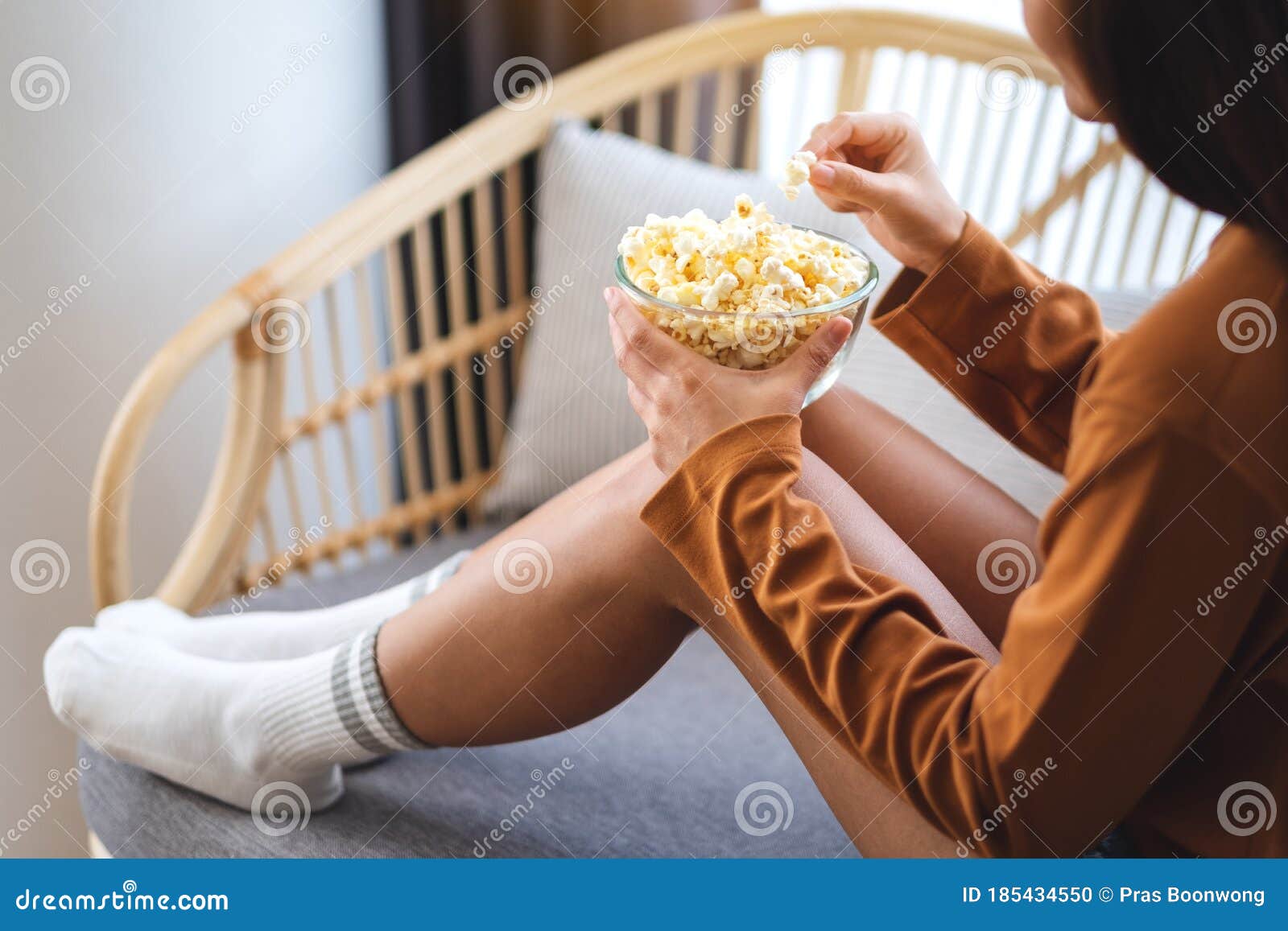 A Beautiful Young Woman Holding And Eating Pop Corn While Sitting On