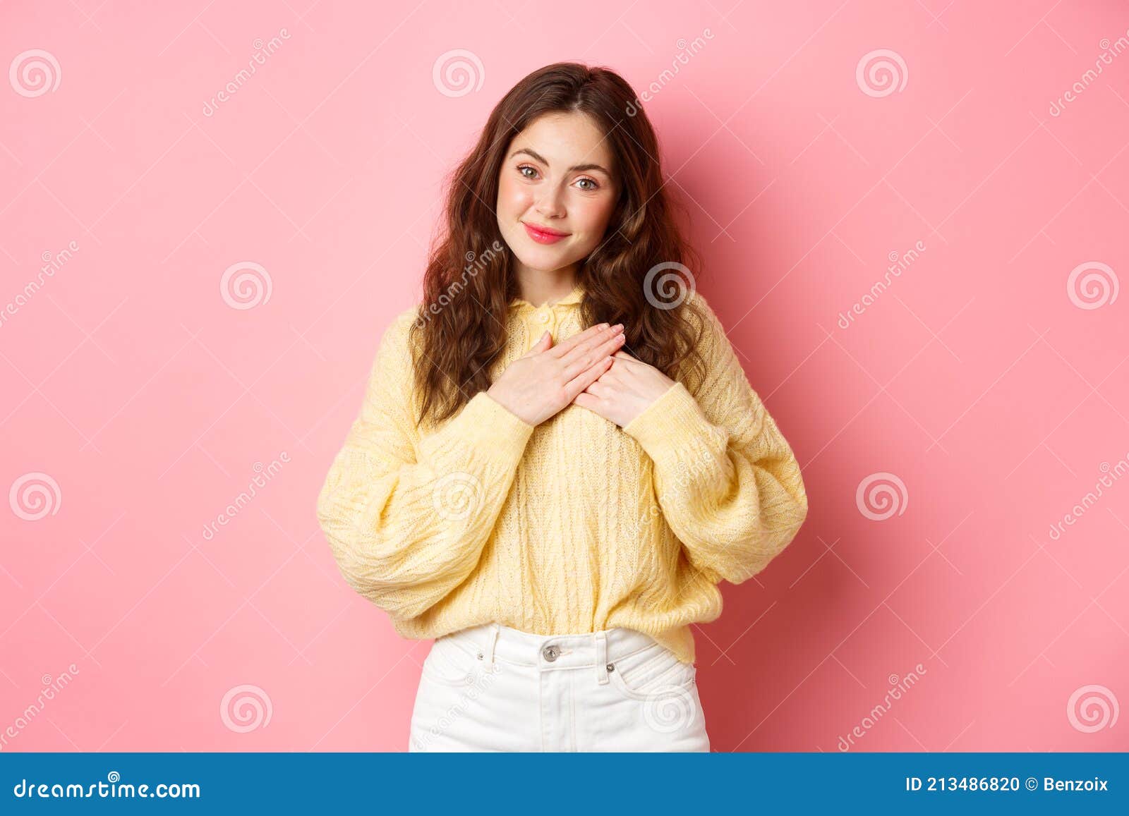 Beautiful Young Woman With Kind Smile Holding Hands On Heart And