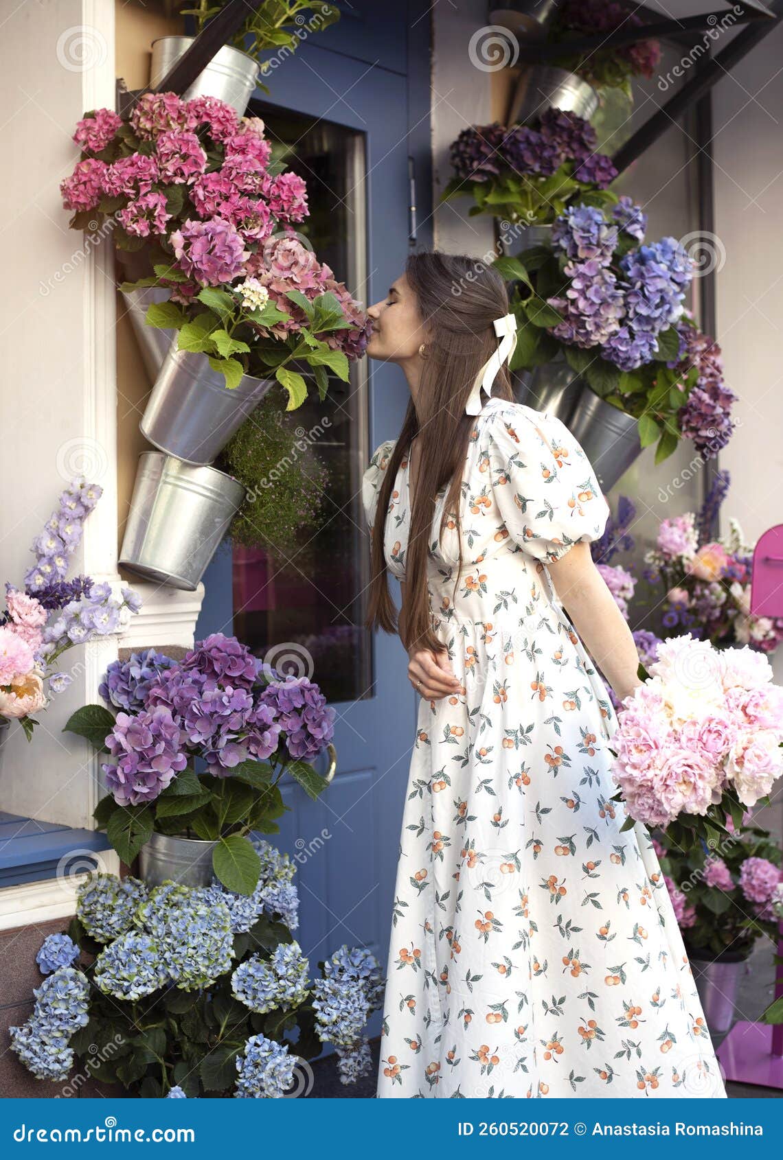 A Beautiful Young Woman With Long Hair In A Dress At A Flower Shop