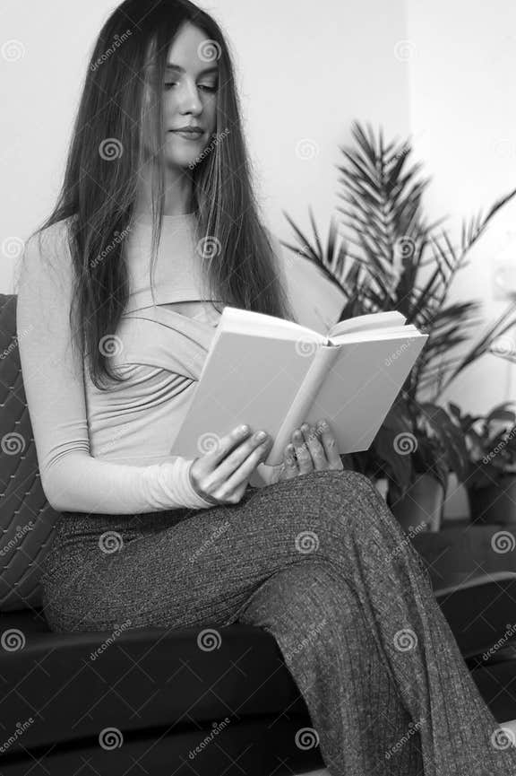 A Beautiful Young Woman Reading A Book Sitting On The Sofa Black And