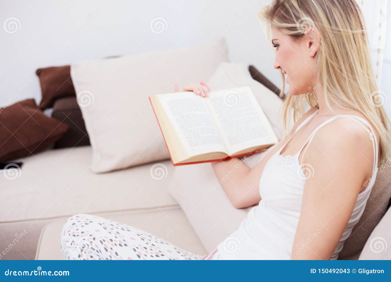 Beautiful Young Woman Sitting In Pajamas And Reading A Book Stock Image