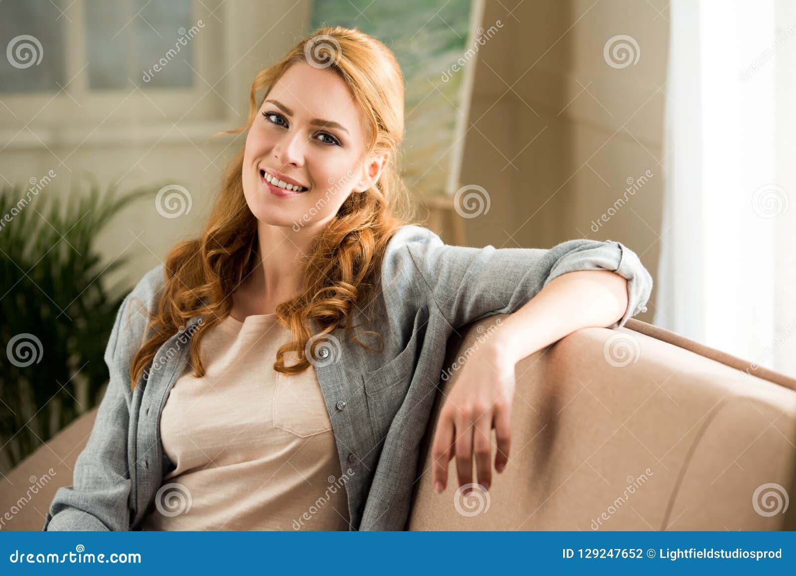 Beautiful Young Woman Sitting on Sofa and Smiling Stock Photo - Image ...