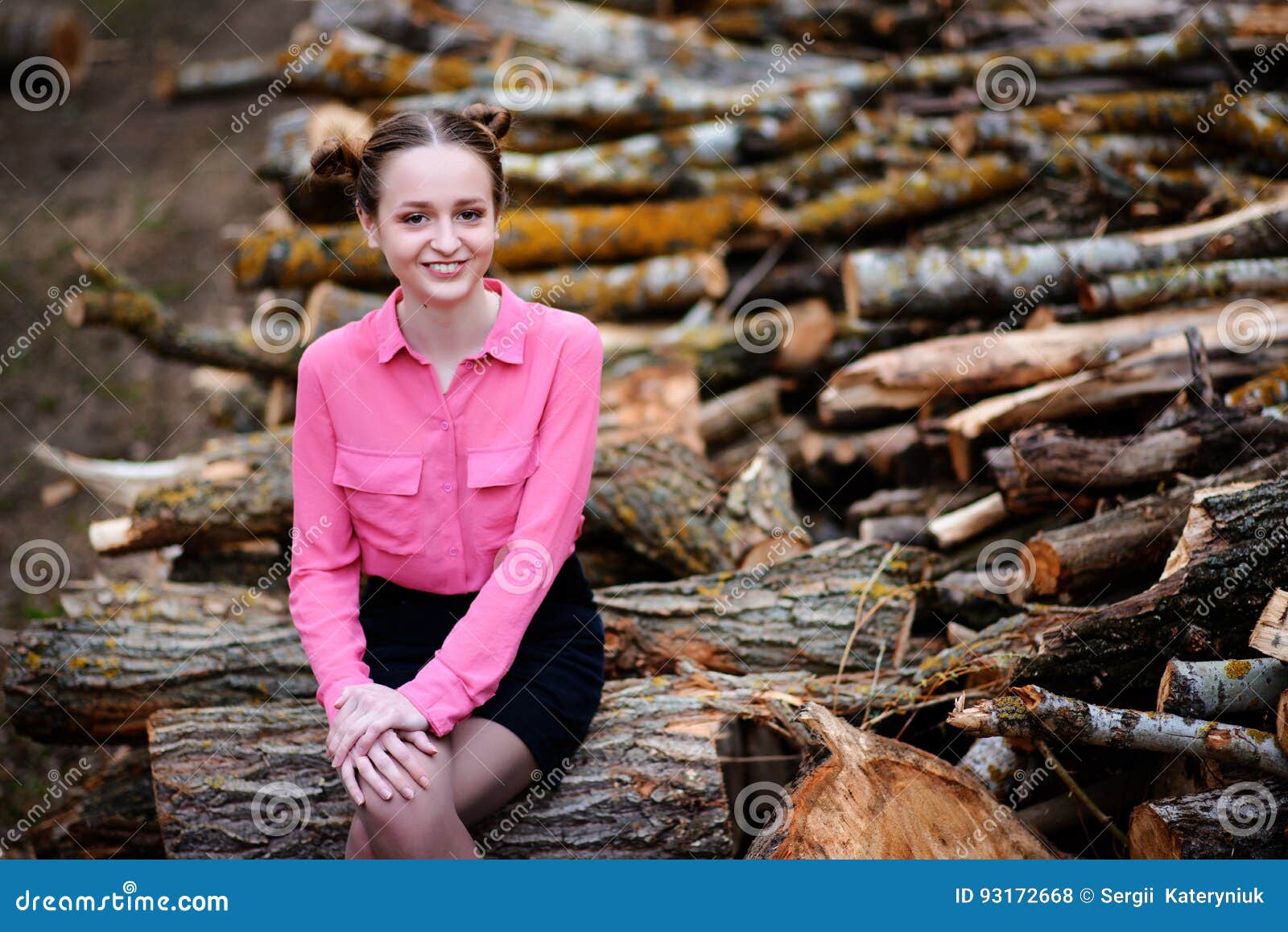 Beautiful Young Woman Sitting on Stack of Felled Tree Trunks in the ...