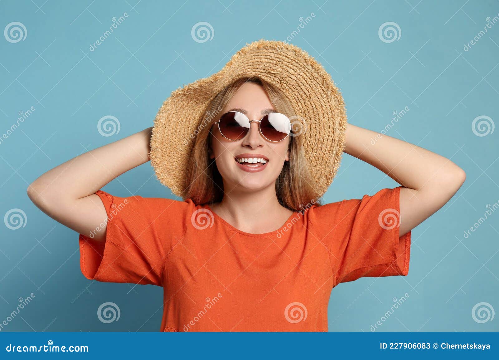 Beautiful Young Woman Wearing Straw Hat And Sunglasses On Light Blue