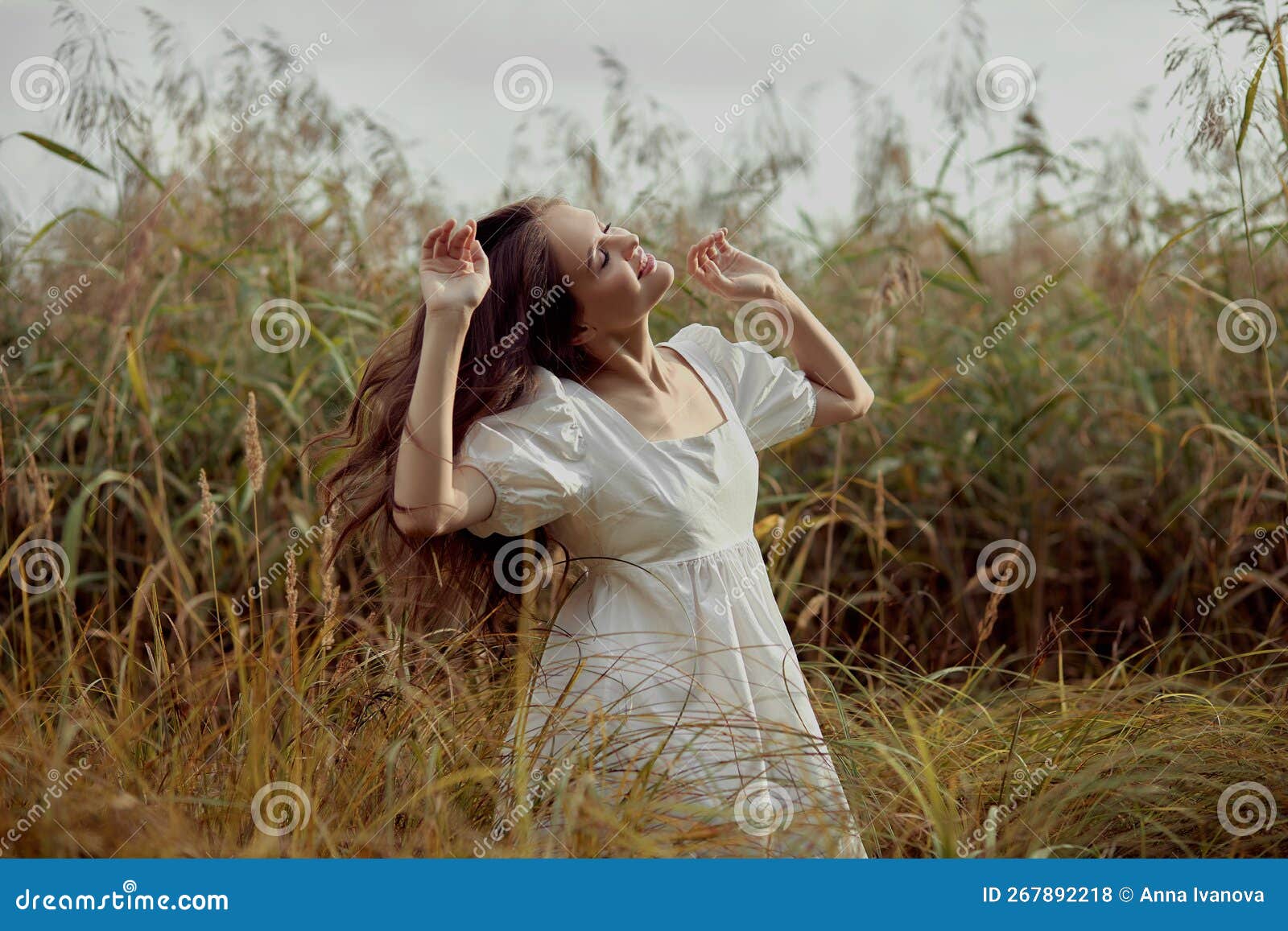 Beautiful Young Woman In White Summer Dress Is Sitting In Tall Grass In