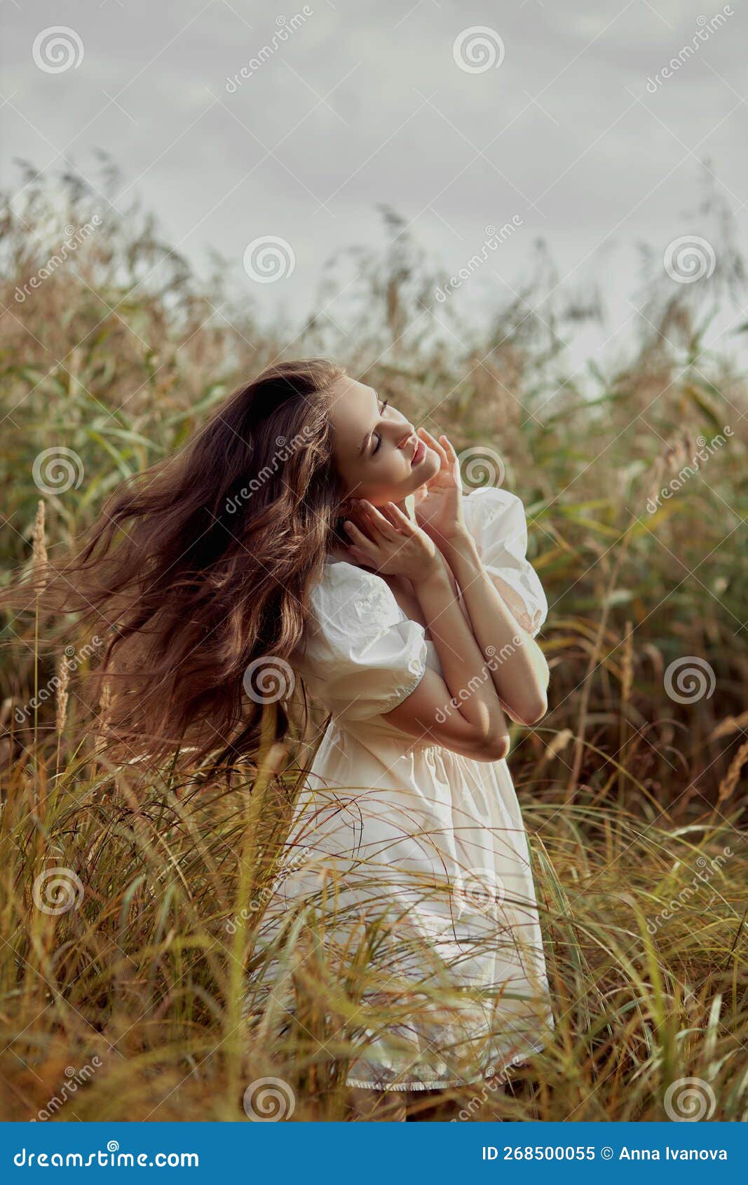 Beautiful Young Woman In White Summer Dress Is Sitting In Tall Grass In