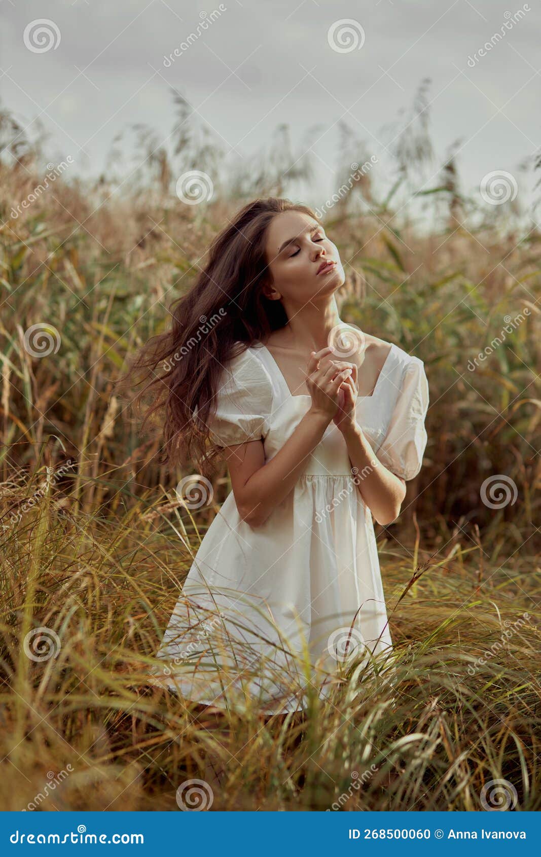 Beautiful Young Woman In White Summer Dress Is Sitting In Tall Grass In