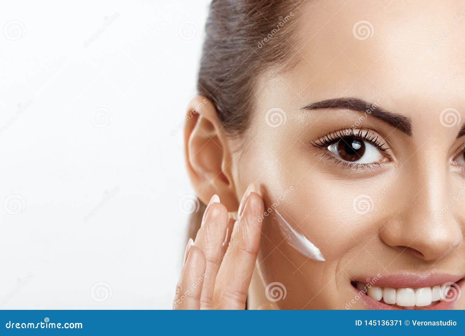 Facial Care Female Applying Cream And Smiling Portrait Of Young Woman